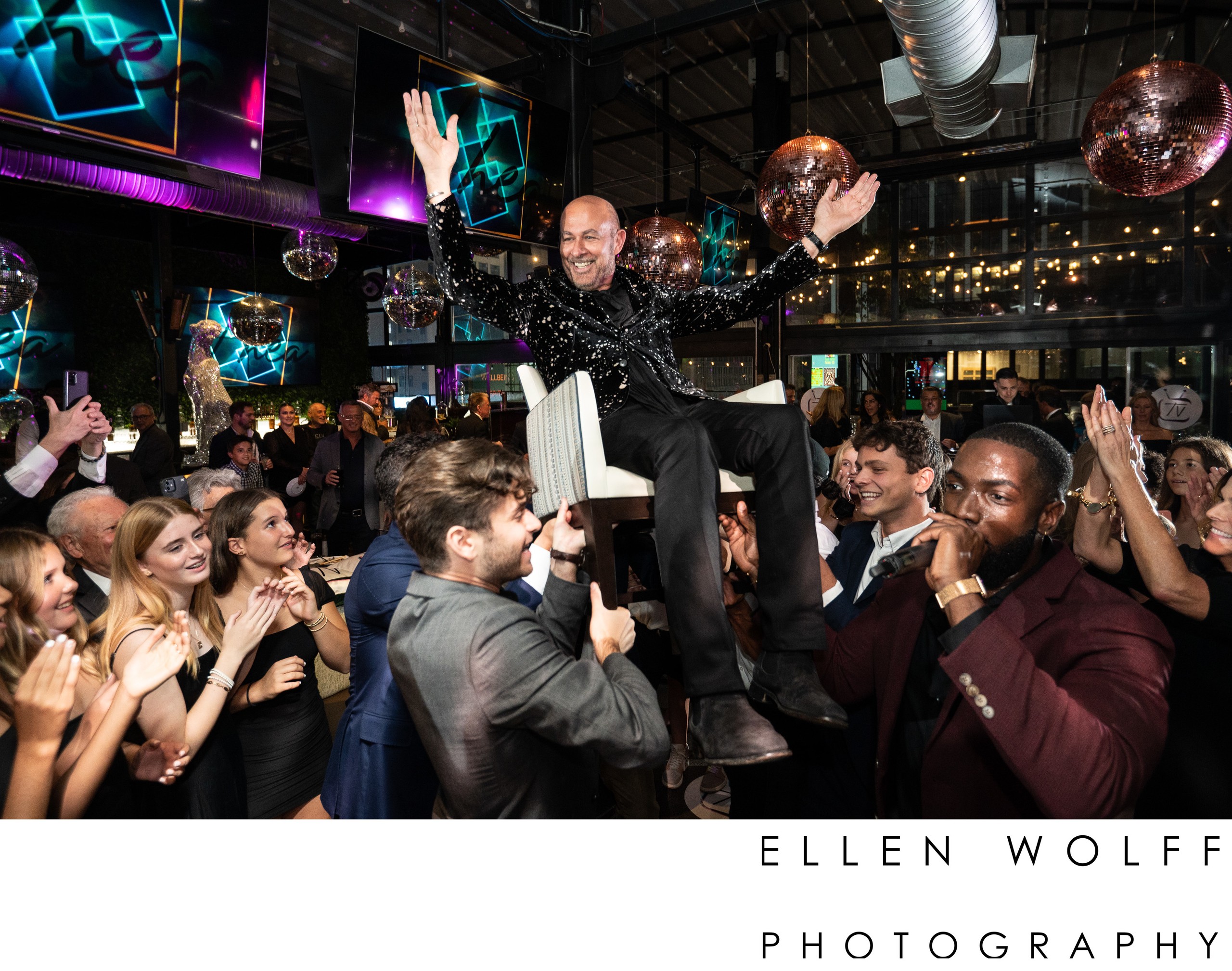 exuberant bat mitzvah dad up in the hora chair - Ellen Wolff Photography